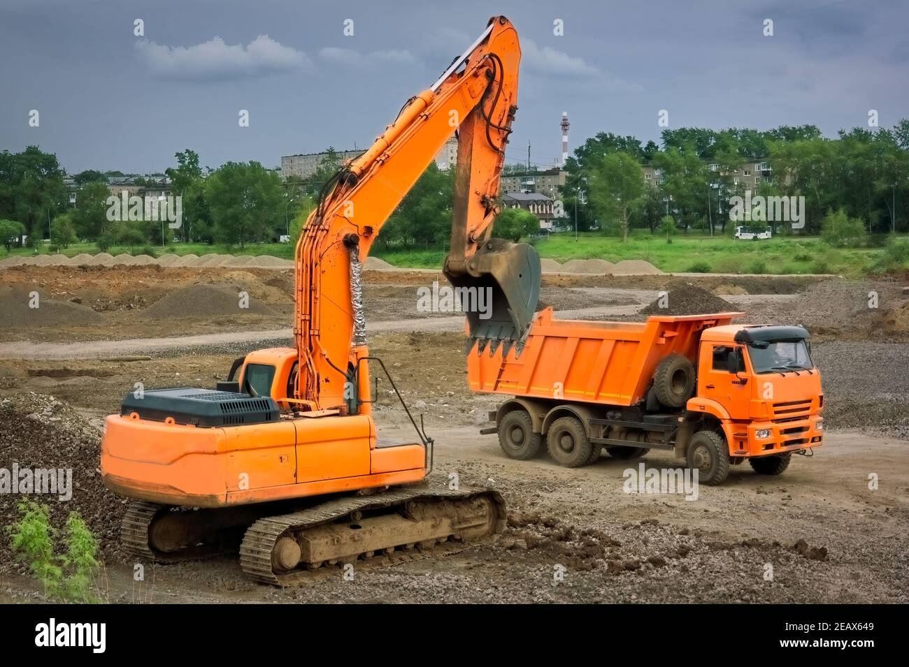 Image of an excavator loading dirt on a dump truck in construction site ...