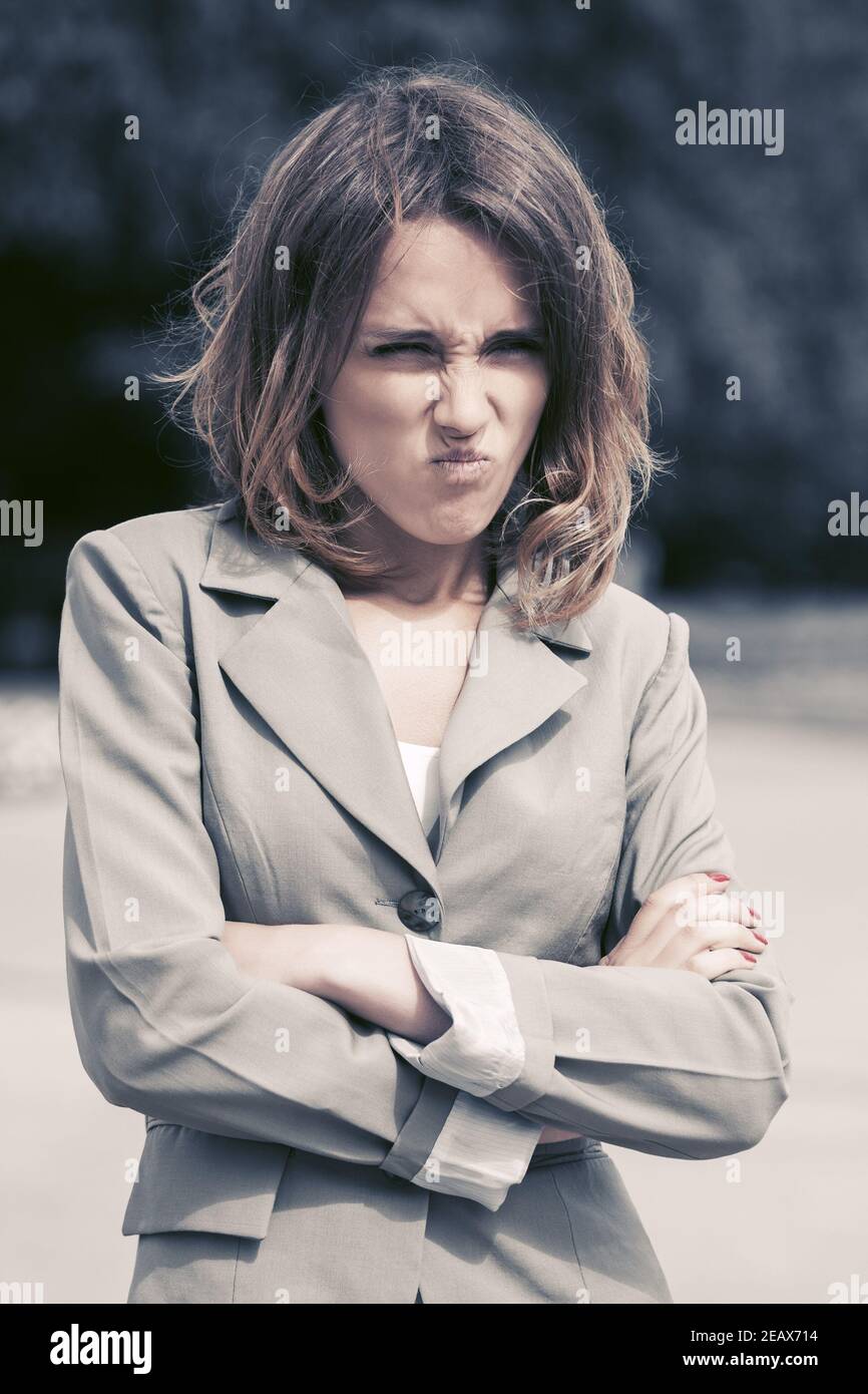 Angry young woman walking on city street Stylish fashion model in gray ...