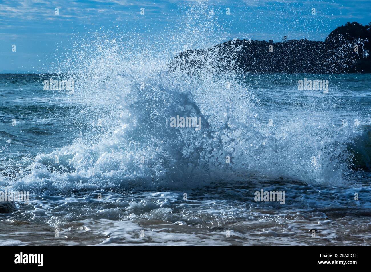 Small waves crashing onto shore where geometric edges of the rocks have ...