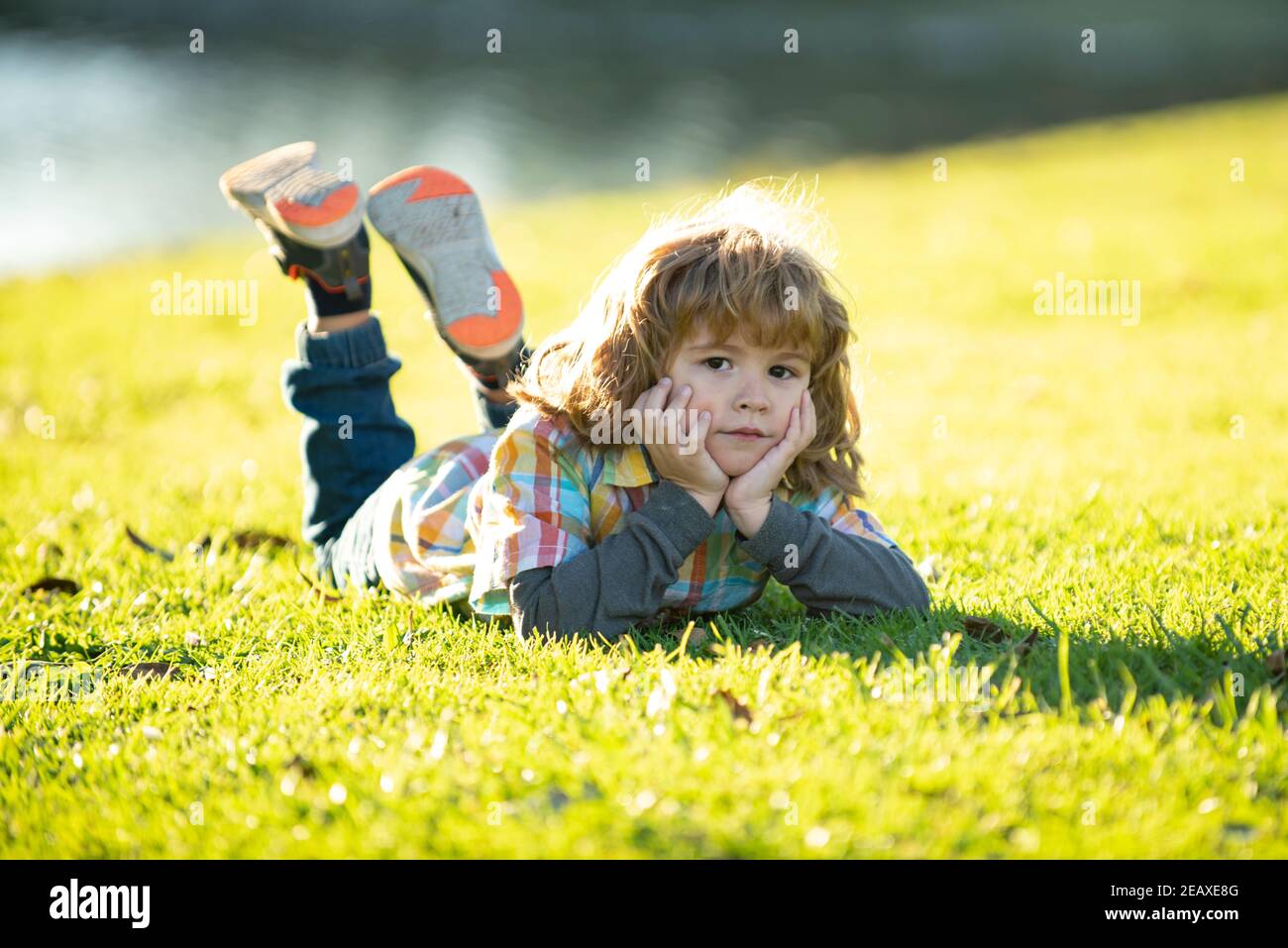 Child outdoor. Kid in park. Spring Boy lying on grass. Summer walk ...