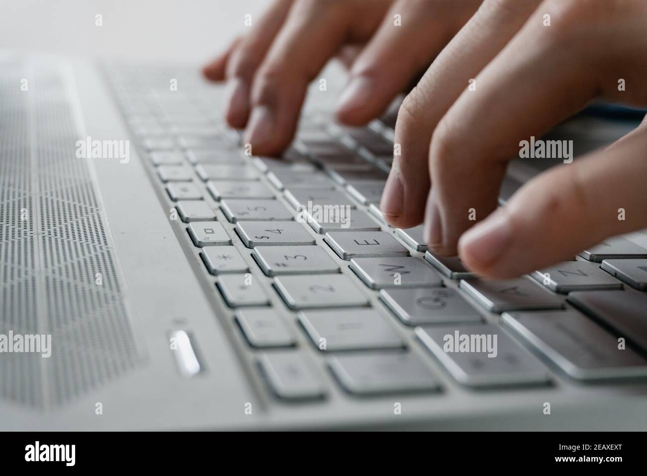 a man's hands typing on the keyboard of a computer all gray and modern ...