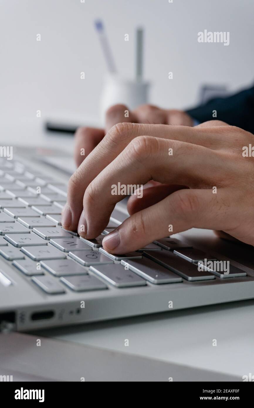 vertical photo of a man typing on his laptop, wearing a suit and a ...