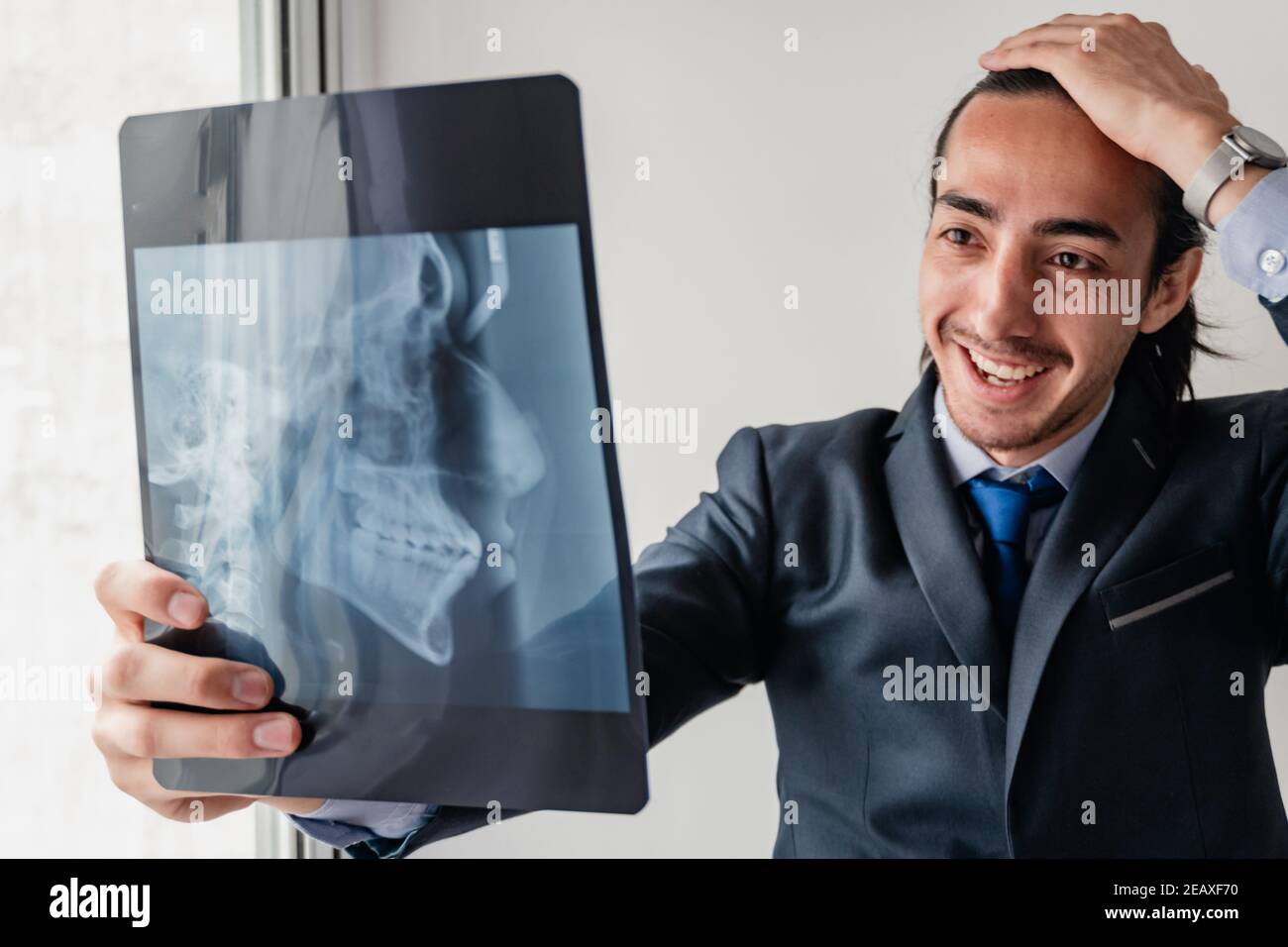 orthodontist looking at a dental profile x-ray with hand on forehead ...