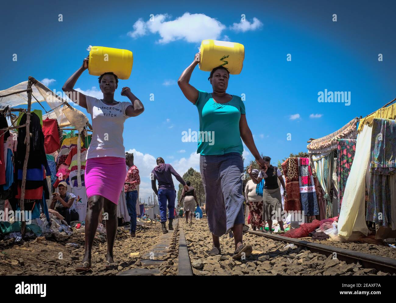 Women walk back home carrying their Water Jerrycans past the busy ...