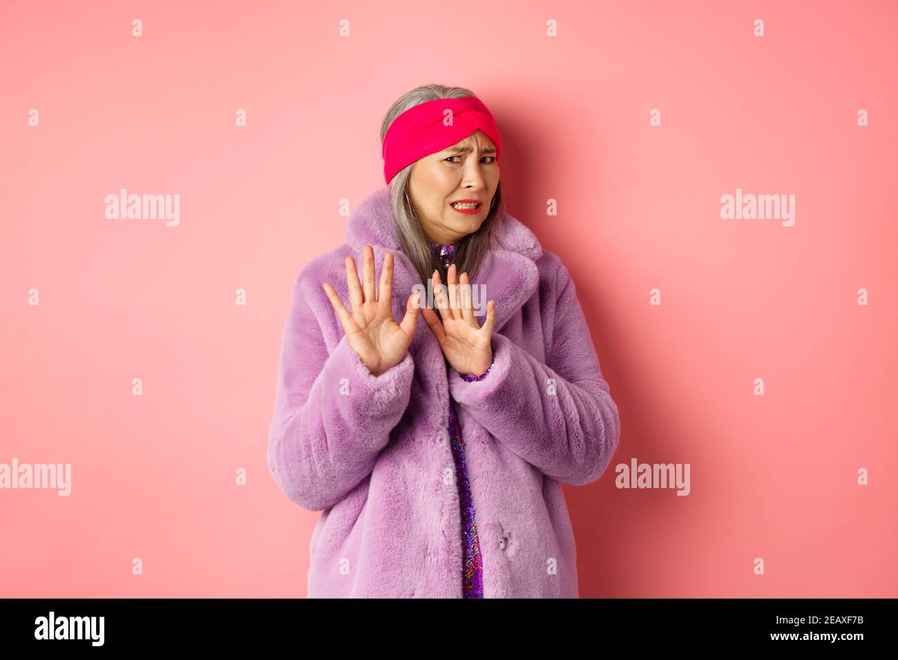 Portrait of stylish asian senior woman in purple winter coat, cringe ...
