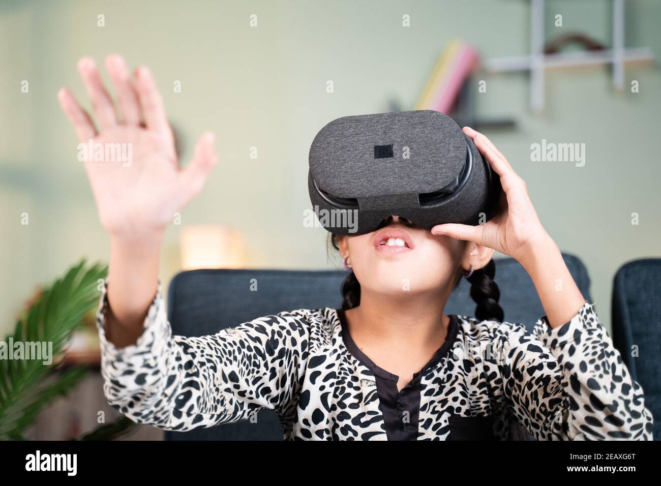 Young girl kid with VR or virtual reality goggles feeling or enjoying ...