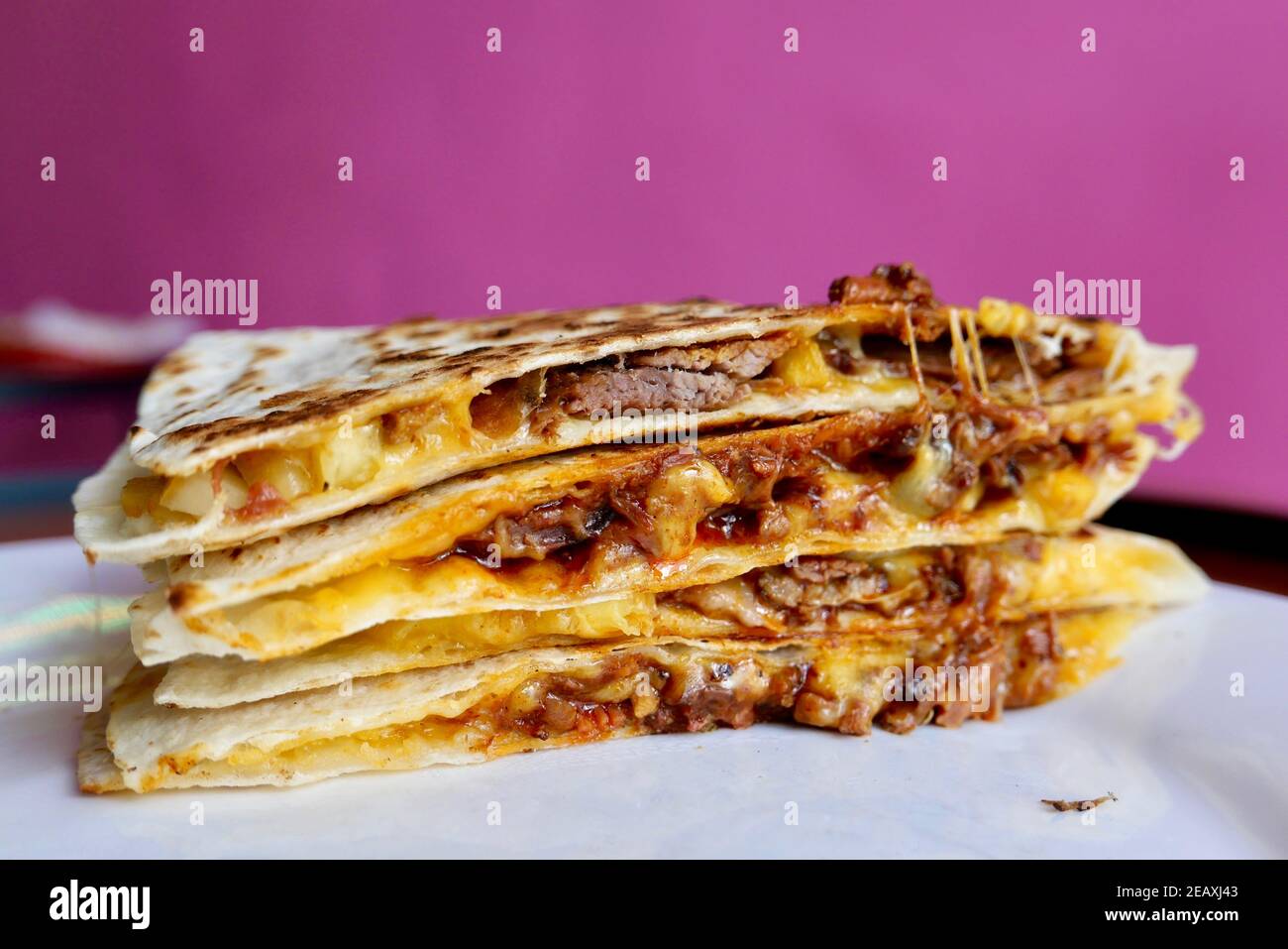 Quesadilla cut open with melted cheese and pink background Stock Photo ...