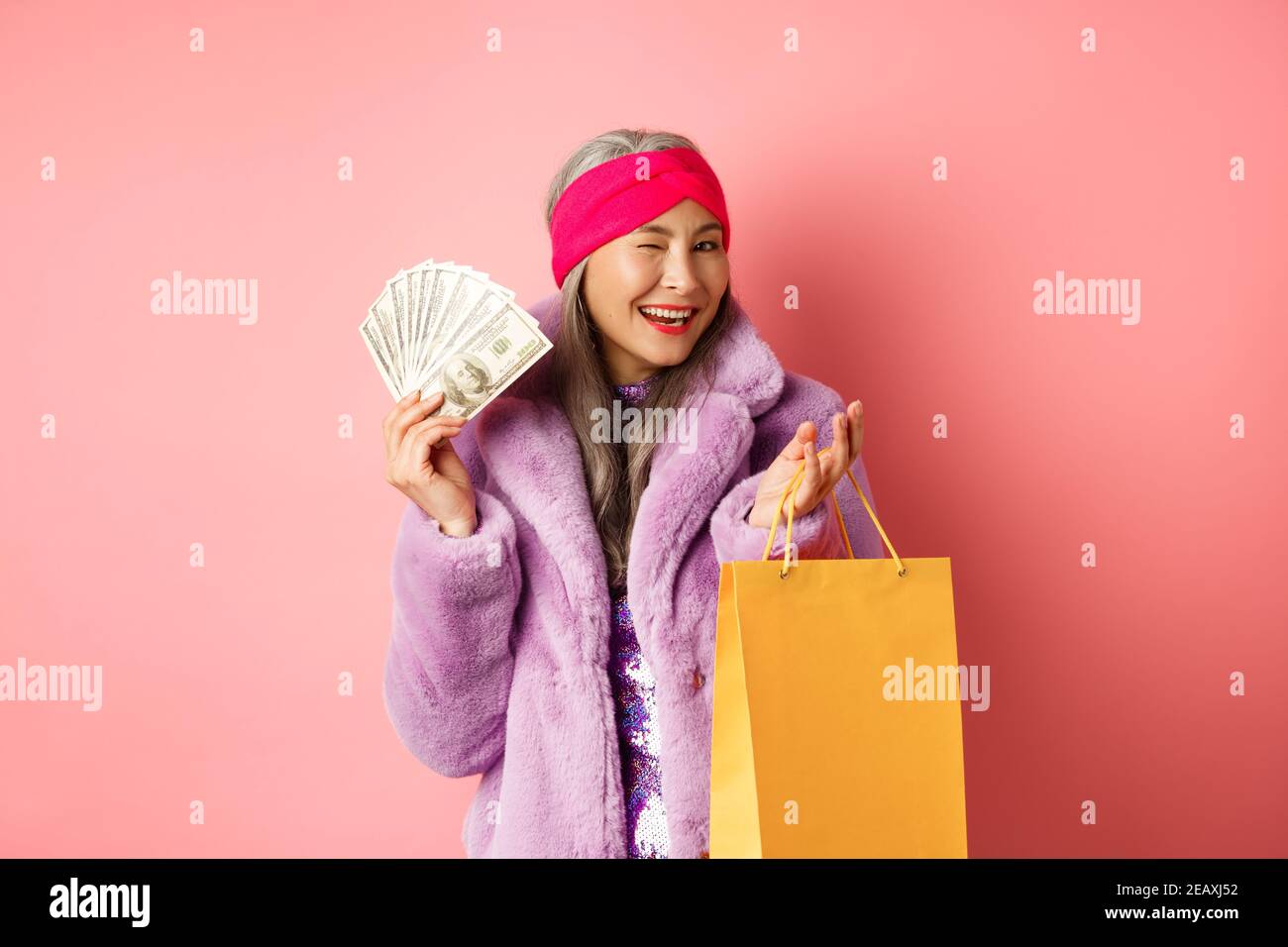 Rich and fashionable asian senior woman wasting money in shops, holding ...