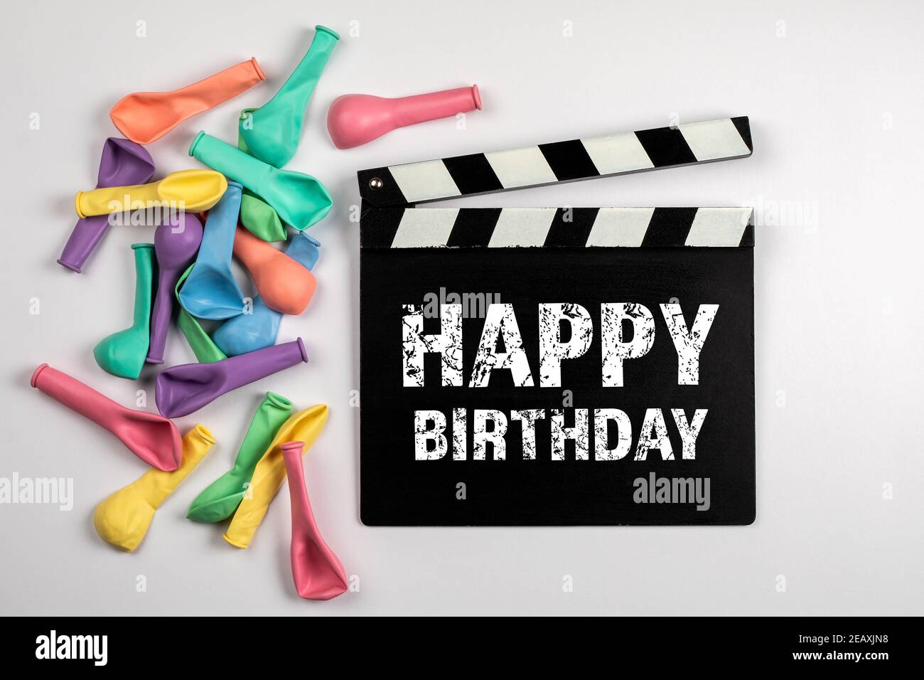 Happy Birthday concept. Coloured balloons and movie clapper on a white ...
