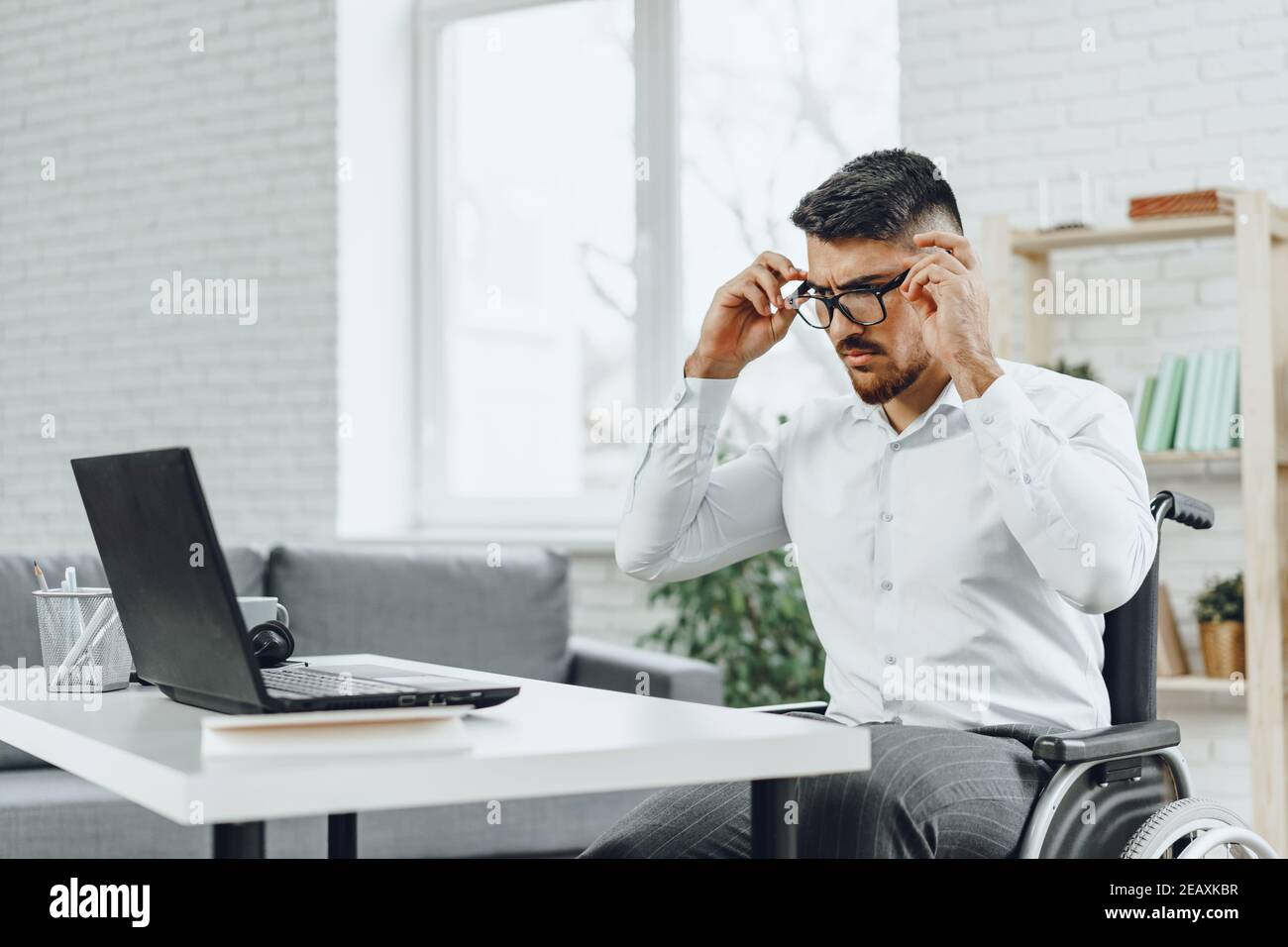 Positive disabled young man in wheelchair working in office Stock Photo ...