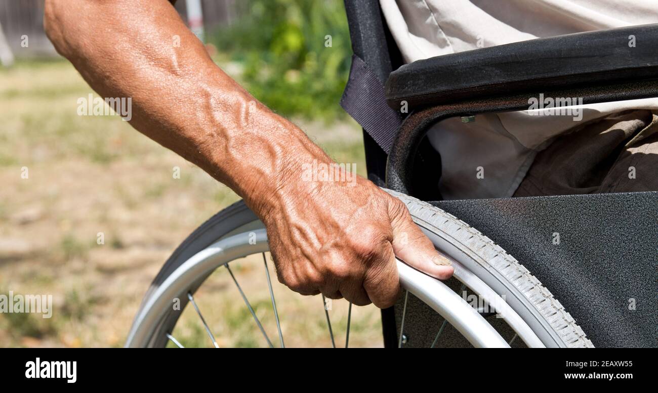 A disabled man is sitting in a wheelchair ,Holds his hands on the wheel ...