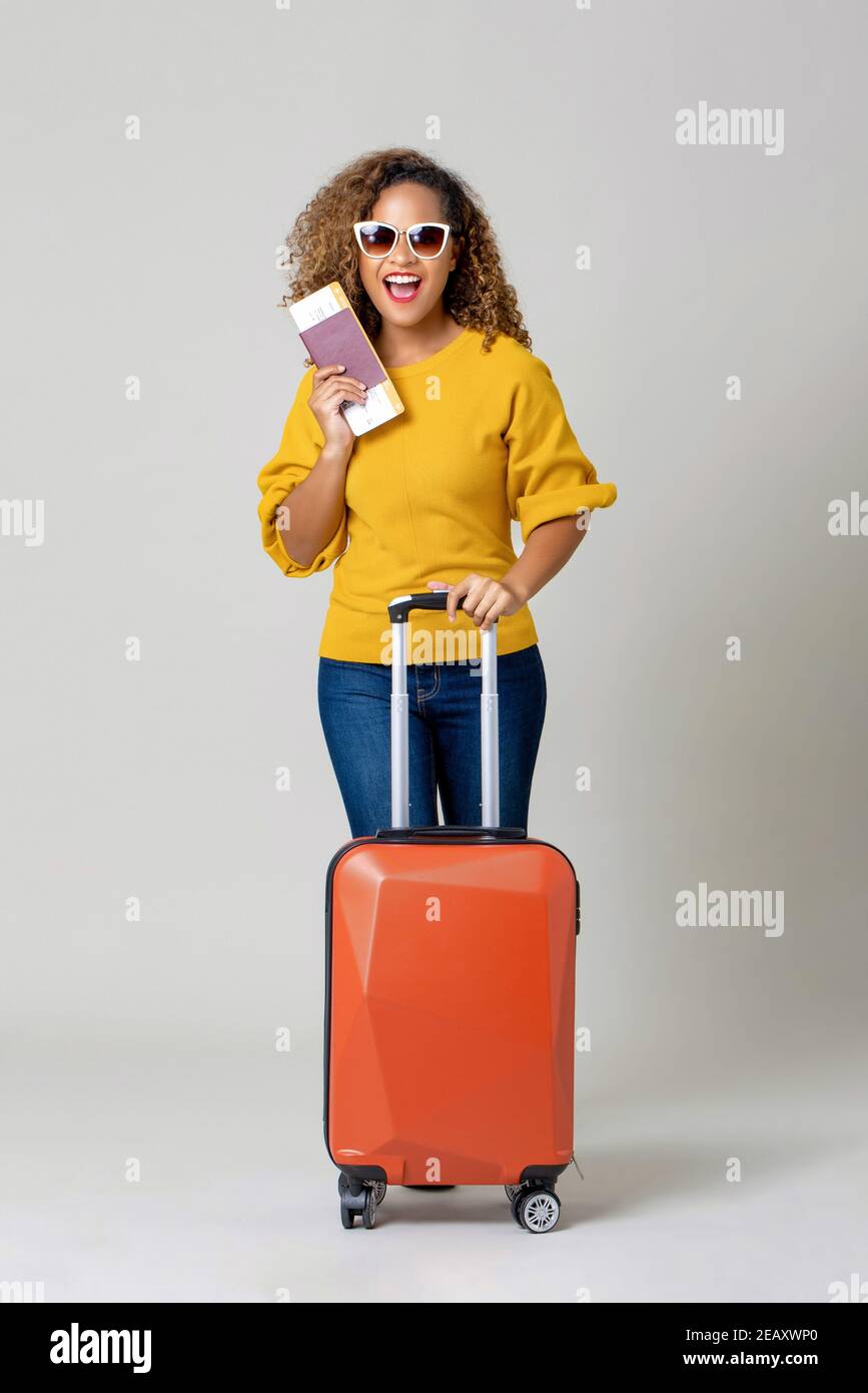 Young African American woman tourist with luggage holding passport and ...