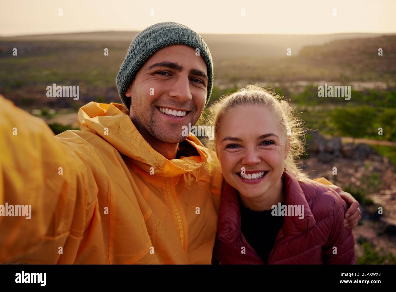Portrait of beautiful young man and woman hugging and smiling after hiking looking at camera ...