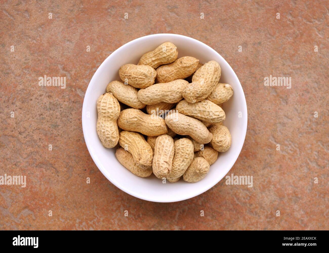 Round ceramic bowl of peanuts in shells. From above. Top view of dried ...