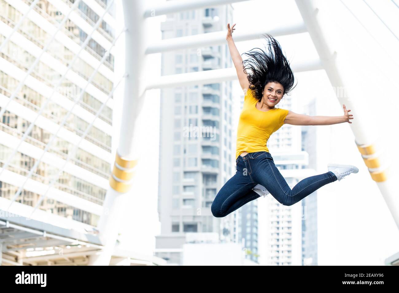 Energetic happy woman jumping with hands outstretched in the city for ...