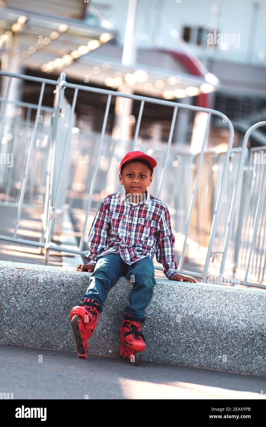 Little african american boy in casual wear and roller skates sitting ...