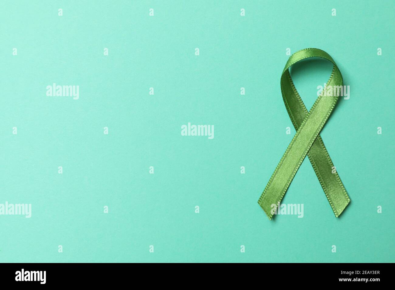 Green awareness ribbon on mint background, space for text Stock Photo ...