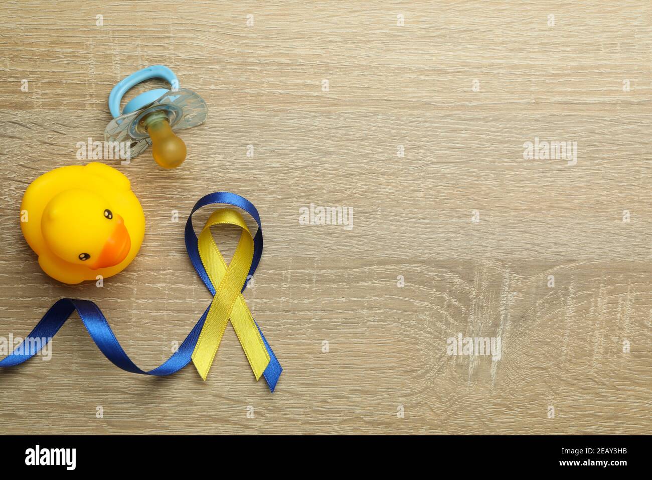 Pacifier, awareness ribbons and rubber duck on wooden background Stock ...