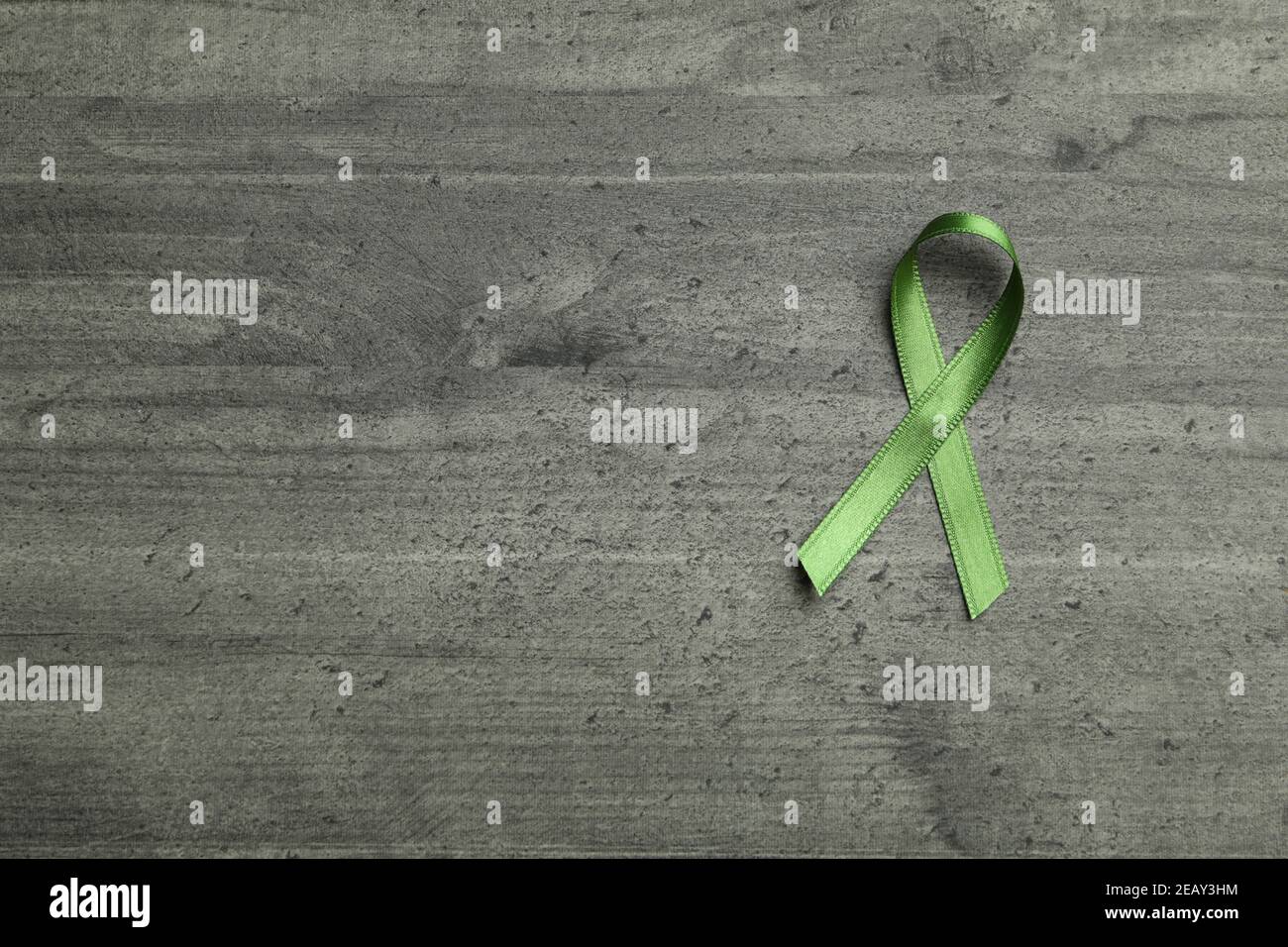 Green awareness ribbon on gray textured background Stock Photo - Alamy