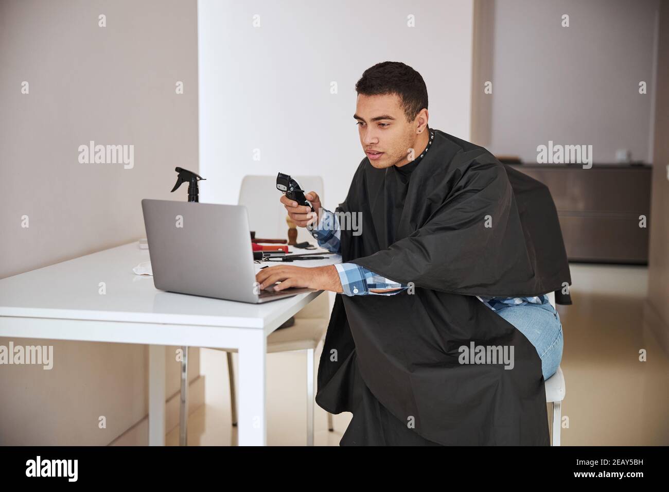 Concentrated man watching something on device at the table in home ...