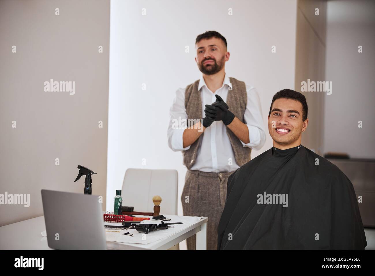 Pleased client with beautiful smile enjoying great hair cut in beauty ...