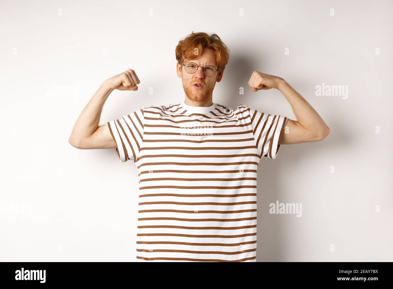 Image of confident and strong redhead man flexing biceps, showing ...