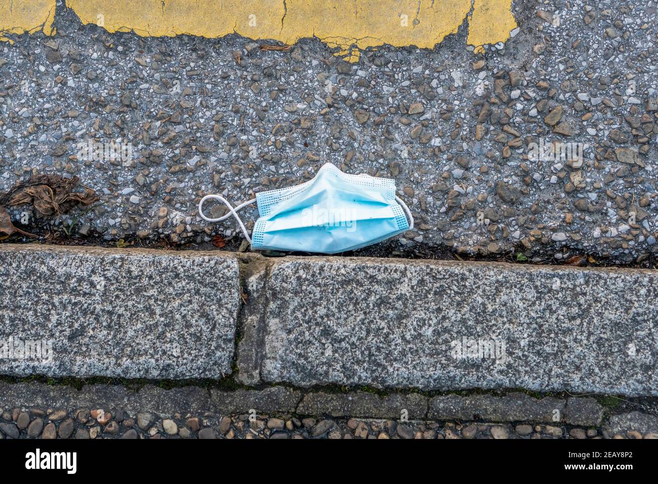 Discarded used disposable medical mask on an asphalt road with old road ...