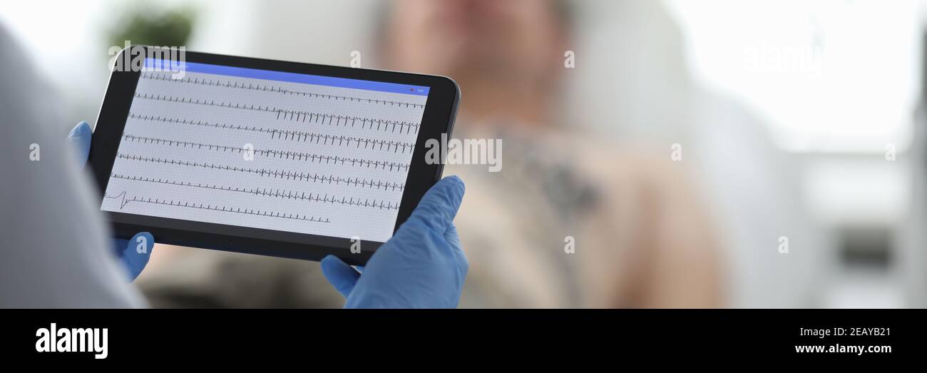 Doctor with ecg monitor stands in front of patient in background Stock ...