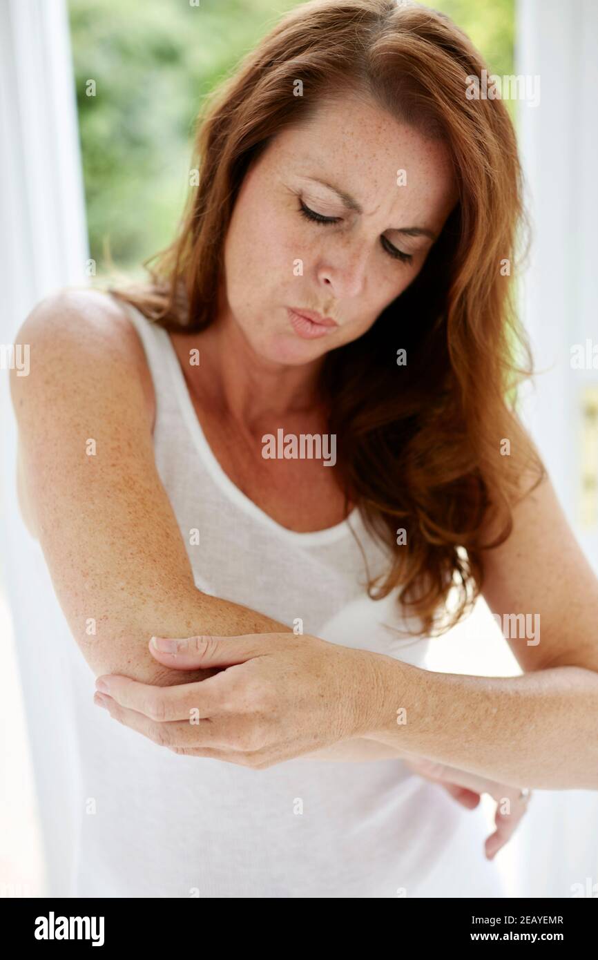 Woman holding her elbow Stock Photo - Alamy