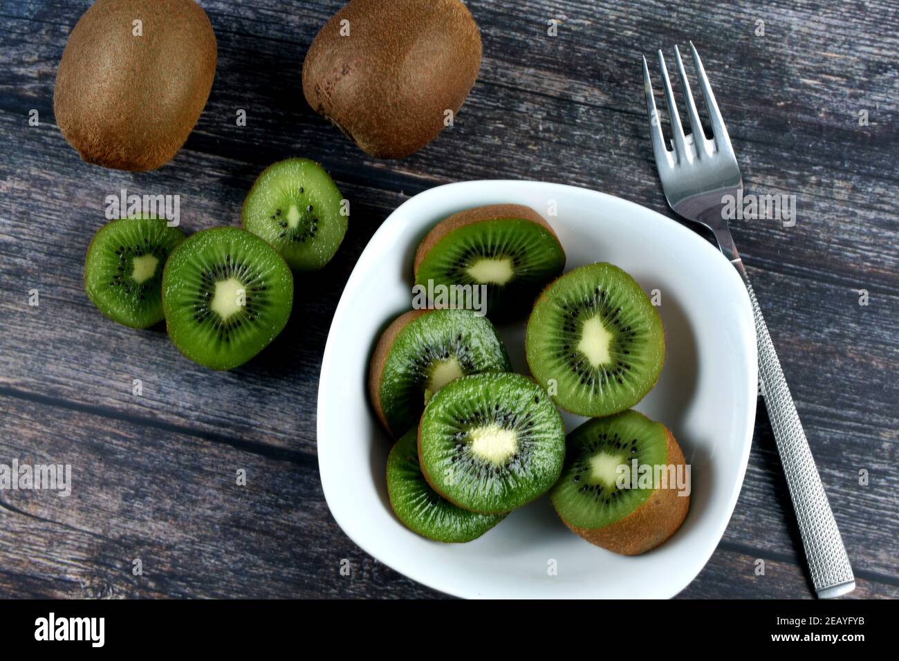 High angle shot of a bowl filled with slices of fresh kiwi on a wooden ...
