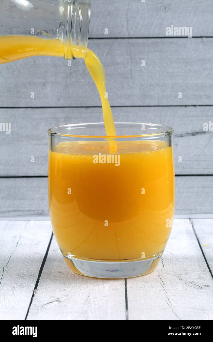 Vertical shot of fresh orange juice being poured into the glass Stock ...