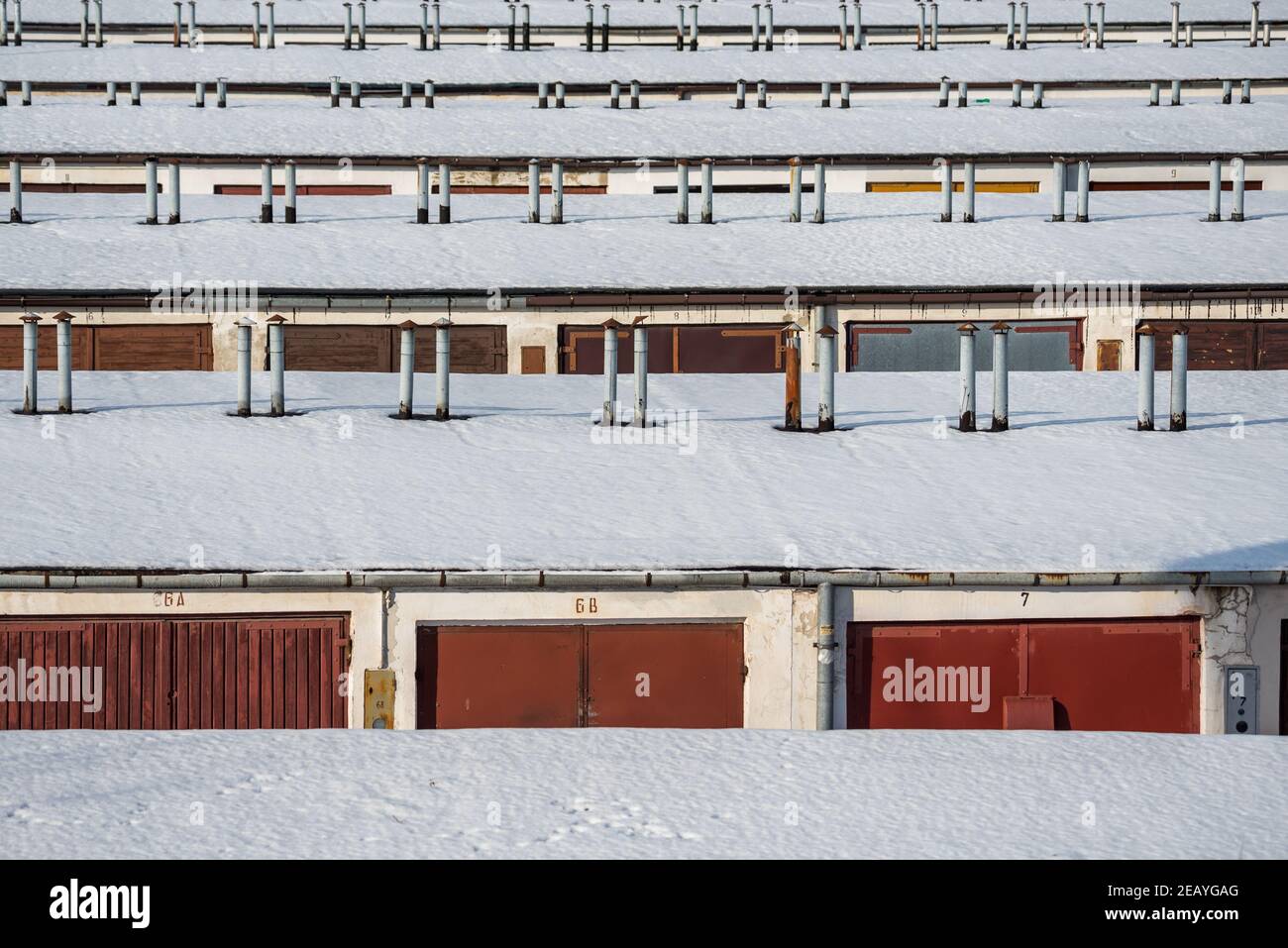 The roofs of urban garages with protruding chimneys covered with snow ...