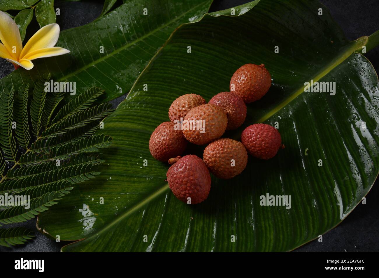 Fresh lychee showing the red skin on green leaf dark background Stock ...
