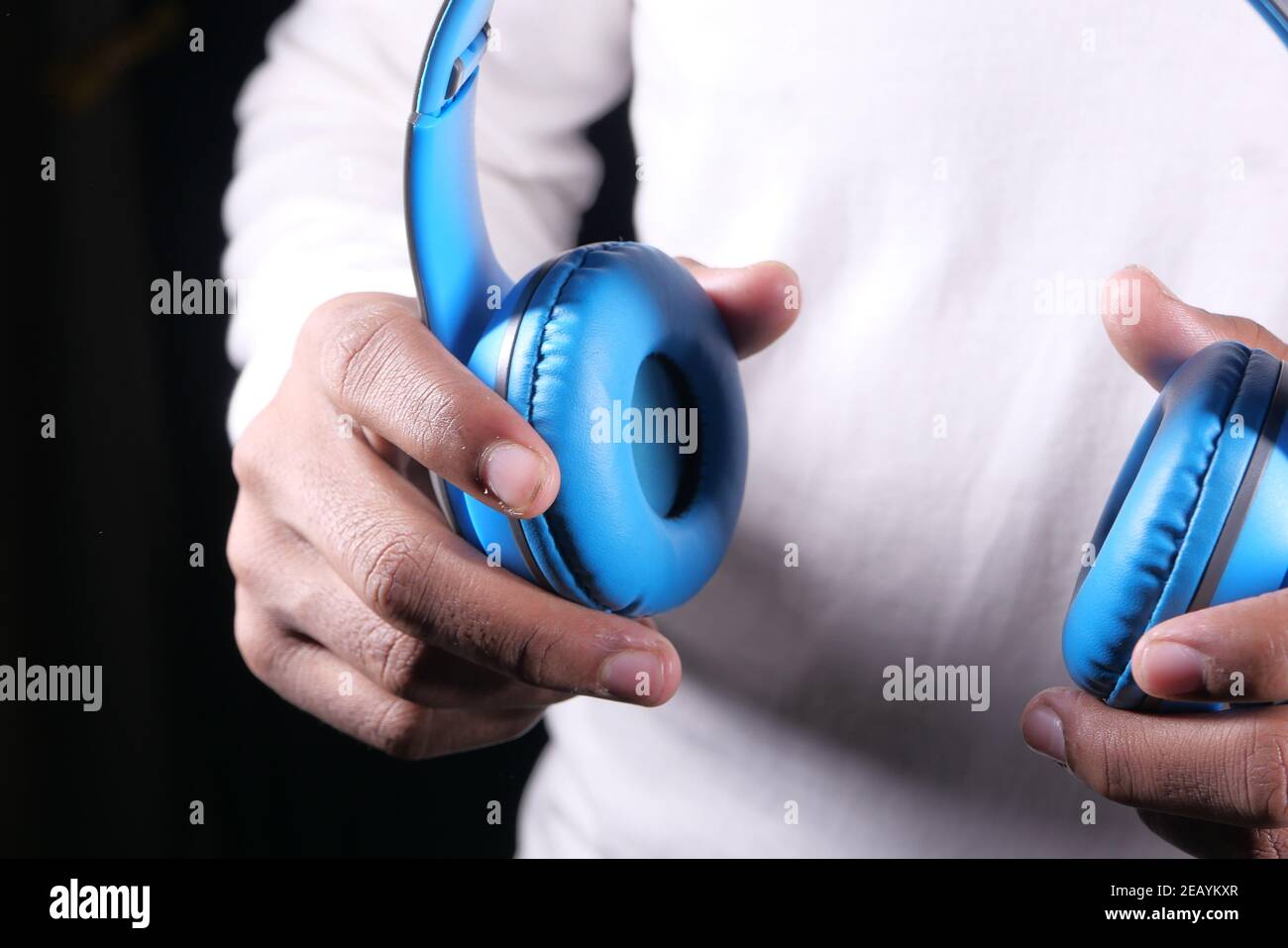 Man hand holding headphone on blue background Stock Photo - Alamy