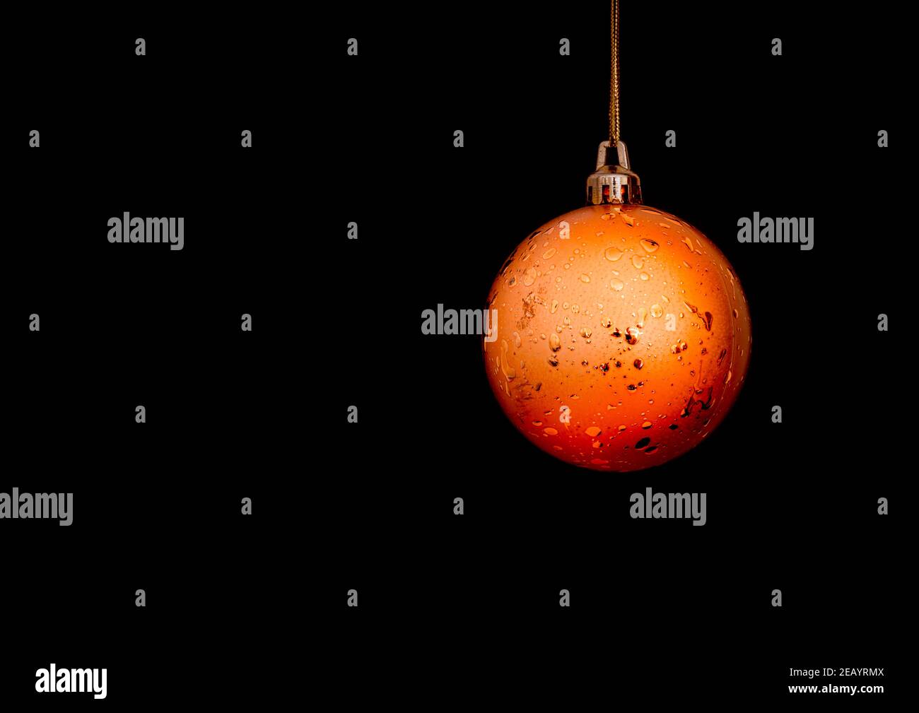 A single orange hanging tree bauble on a plain black background Stock ...