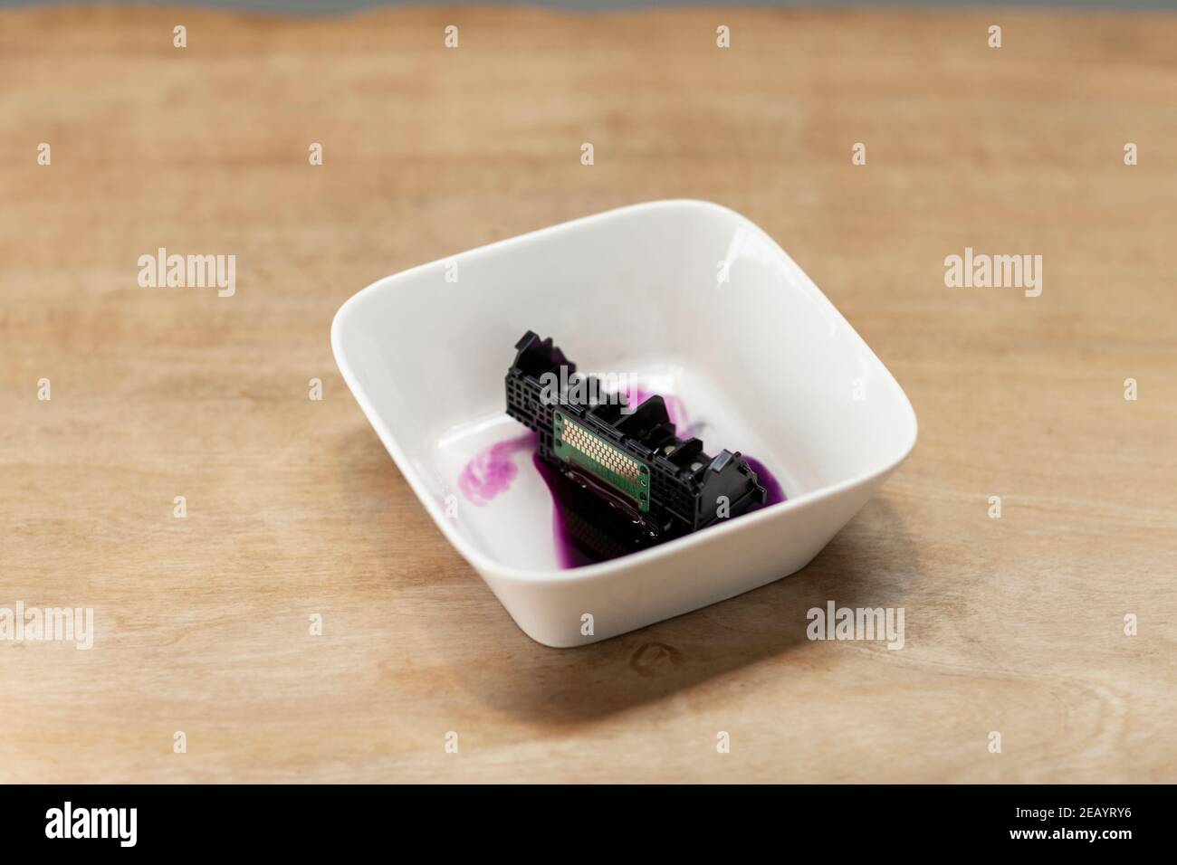 A clogged printhead from an inktjet printer being washed in a white ...