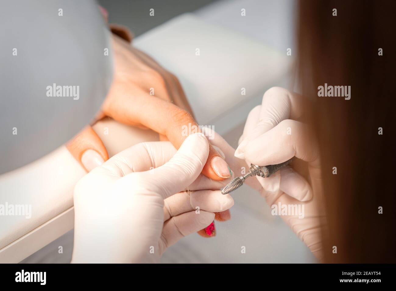 Closeup of manicure master removes nail polish uses an electric nail ...