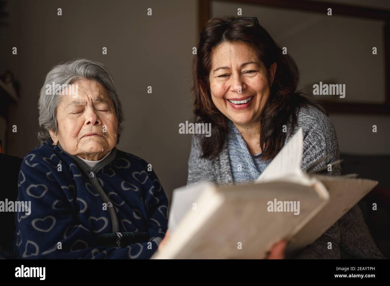 Old sick woman with memory loss. Smiling daughter showing a photo album ...