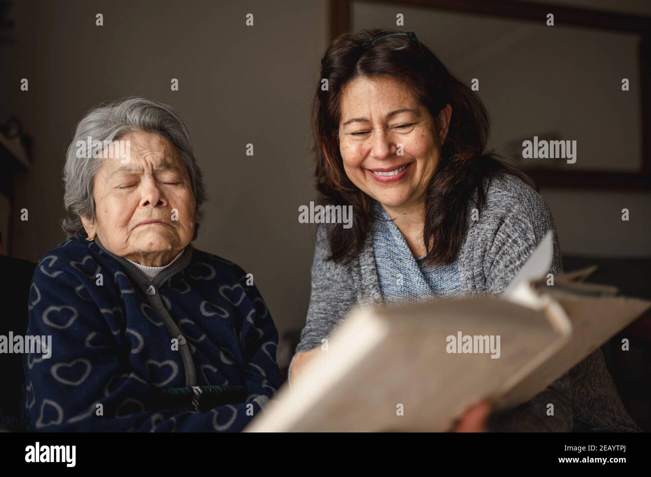 Old sick woman with memory loss. Smiling daughter showing a photo album ...