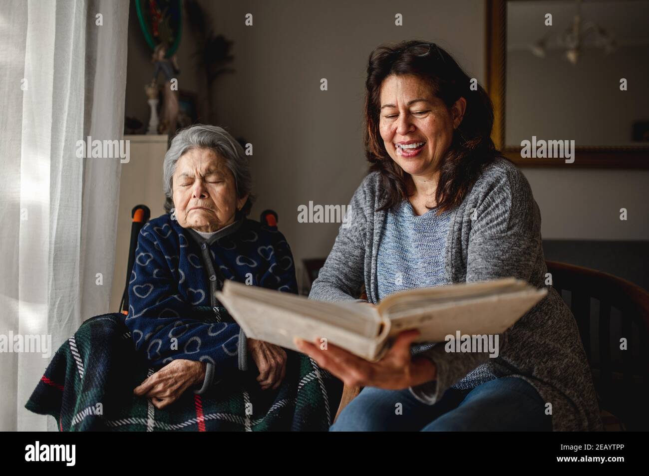 Old sick woman with memory loss sitting in wheelchair. Smiling daughter ...