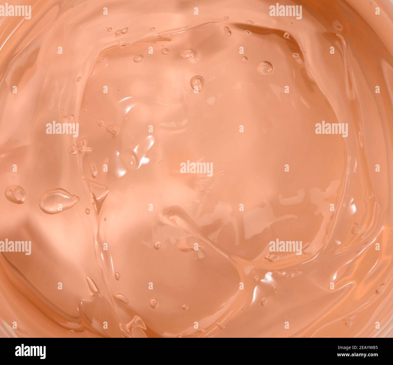 texture of orange moisturizing translucent cream in a plastic jar, top ...