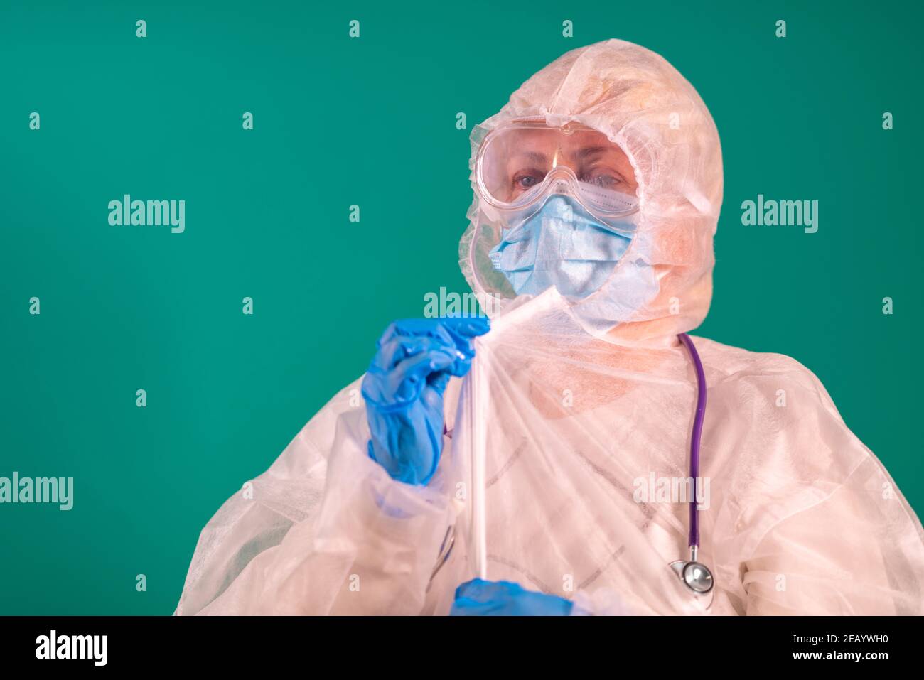 A doctor puts on a PPE suit uniform with a stethoscope on the shoulder ...