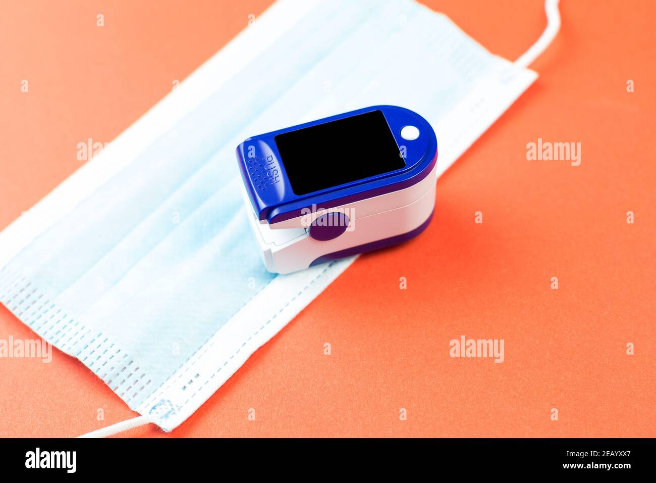 Pulse oximeter and protective medical mask on orange background Stock ...