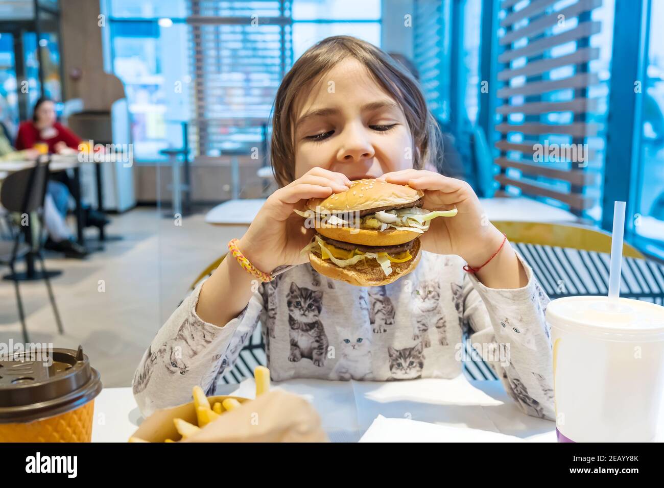 Child girl eating a big burger. Selective focus Stock Photo - Alamy