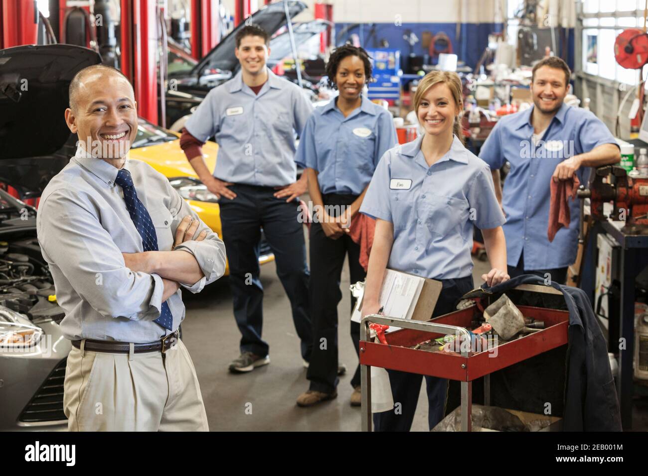 Portrait of smiling auto repair shop team with Pacific Islander owner ...