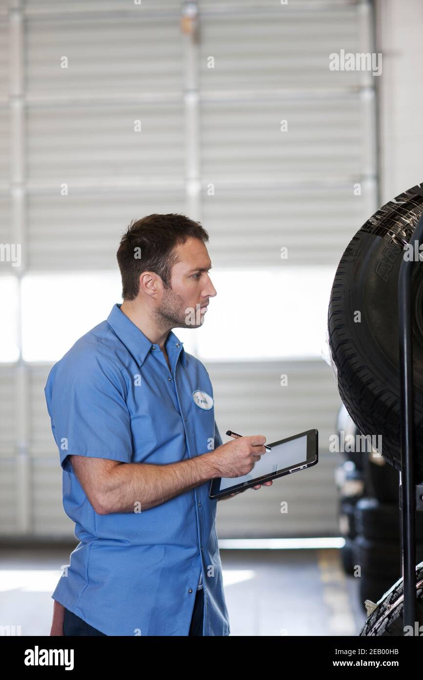 Male mechanic taking inventory of new tires in auto repair shop Stock ...