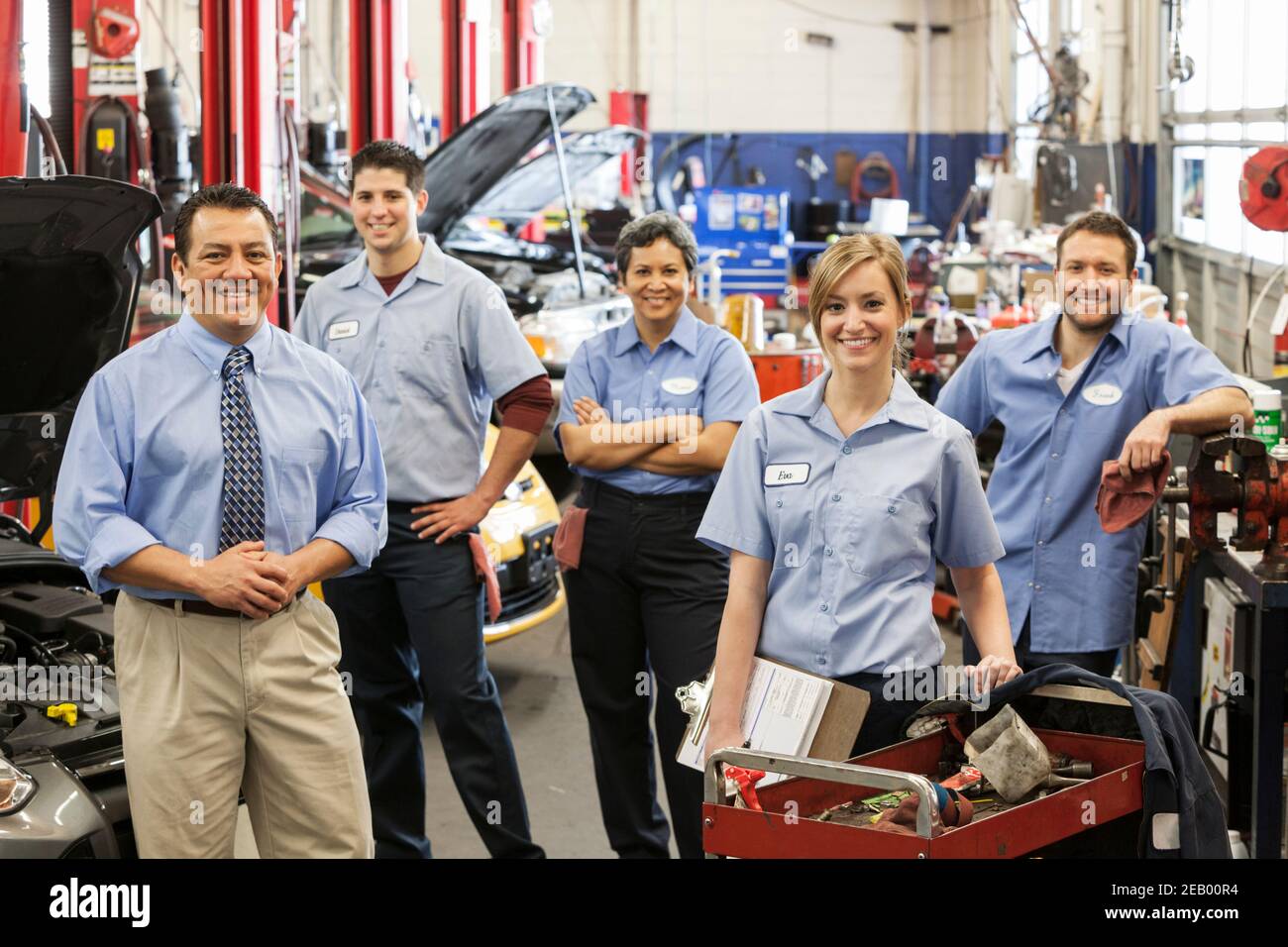Portrait of smiling auto repair shop team with Hispanic male owner ...