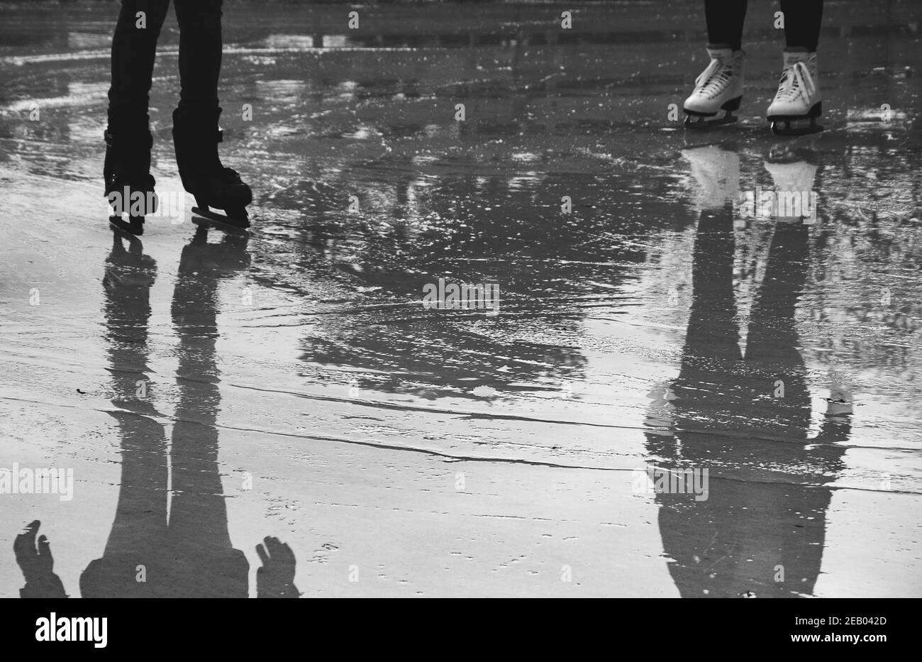Two girls skating on wet melting ice rink. Beginner and professional ...