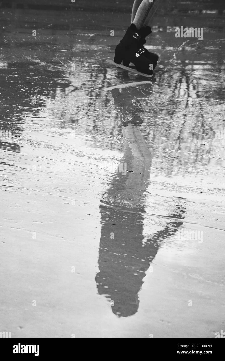 Girl wearing skates learning to skate on wet melting ice rink. Beginner ...