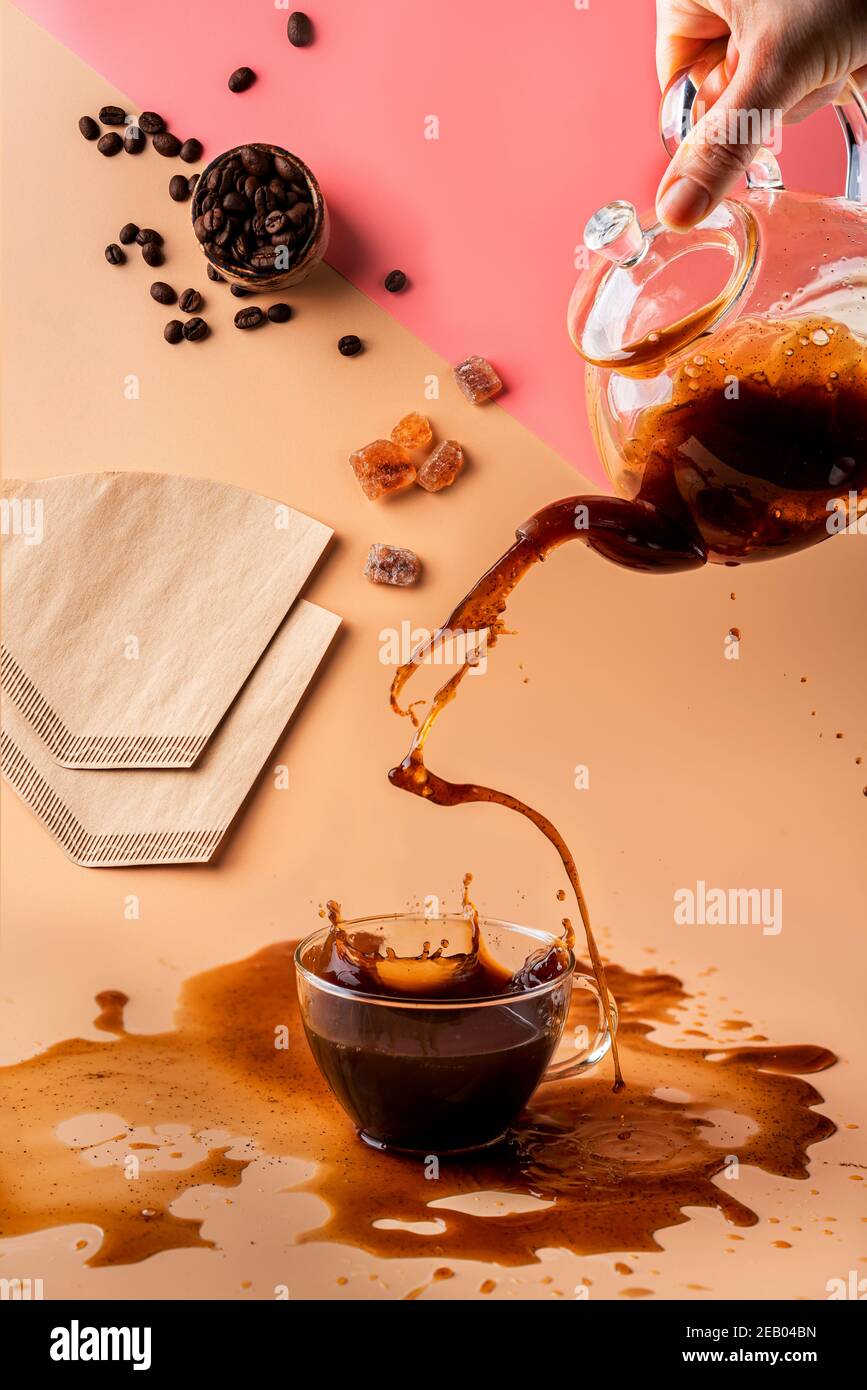 pouring coffee in a cup creating splashes with ingredients on colorful ...